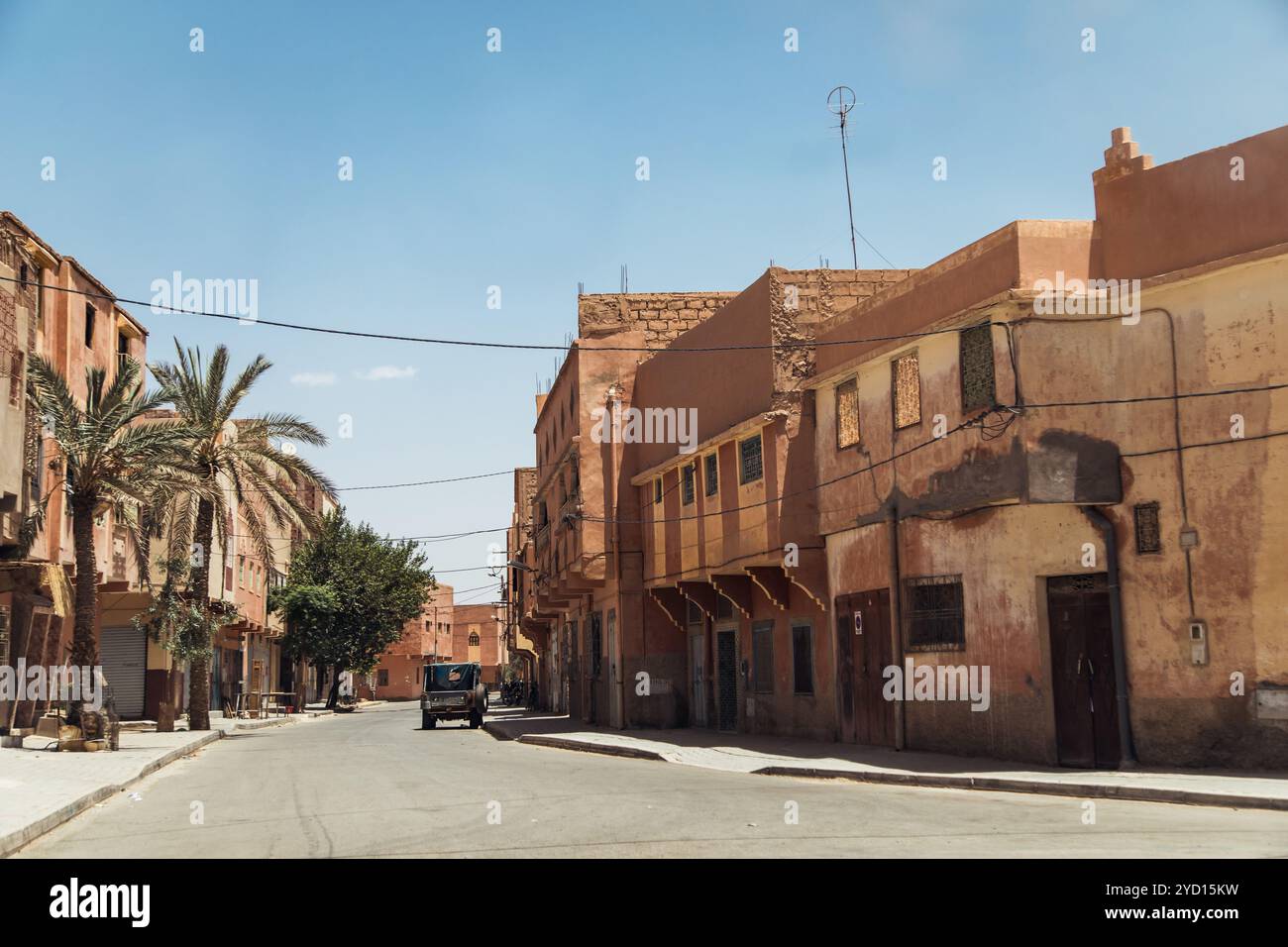 A quiet, sunlit street in a Moroccan neighborhood features beige ...