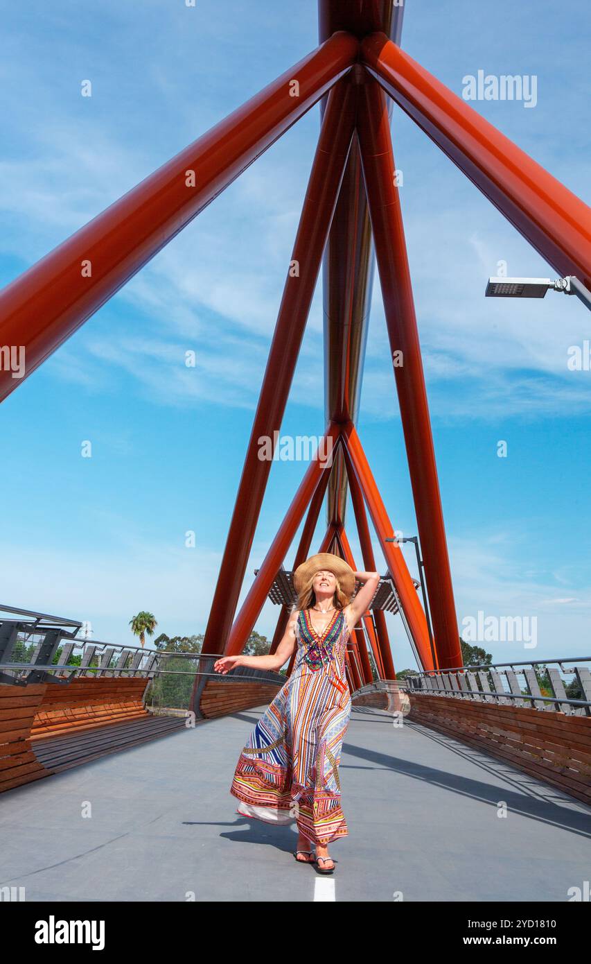 Female in long dress of vibrant patterns walking across Yandhai Nepean ...