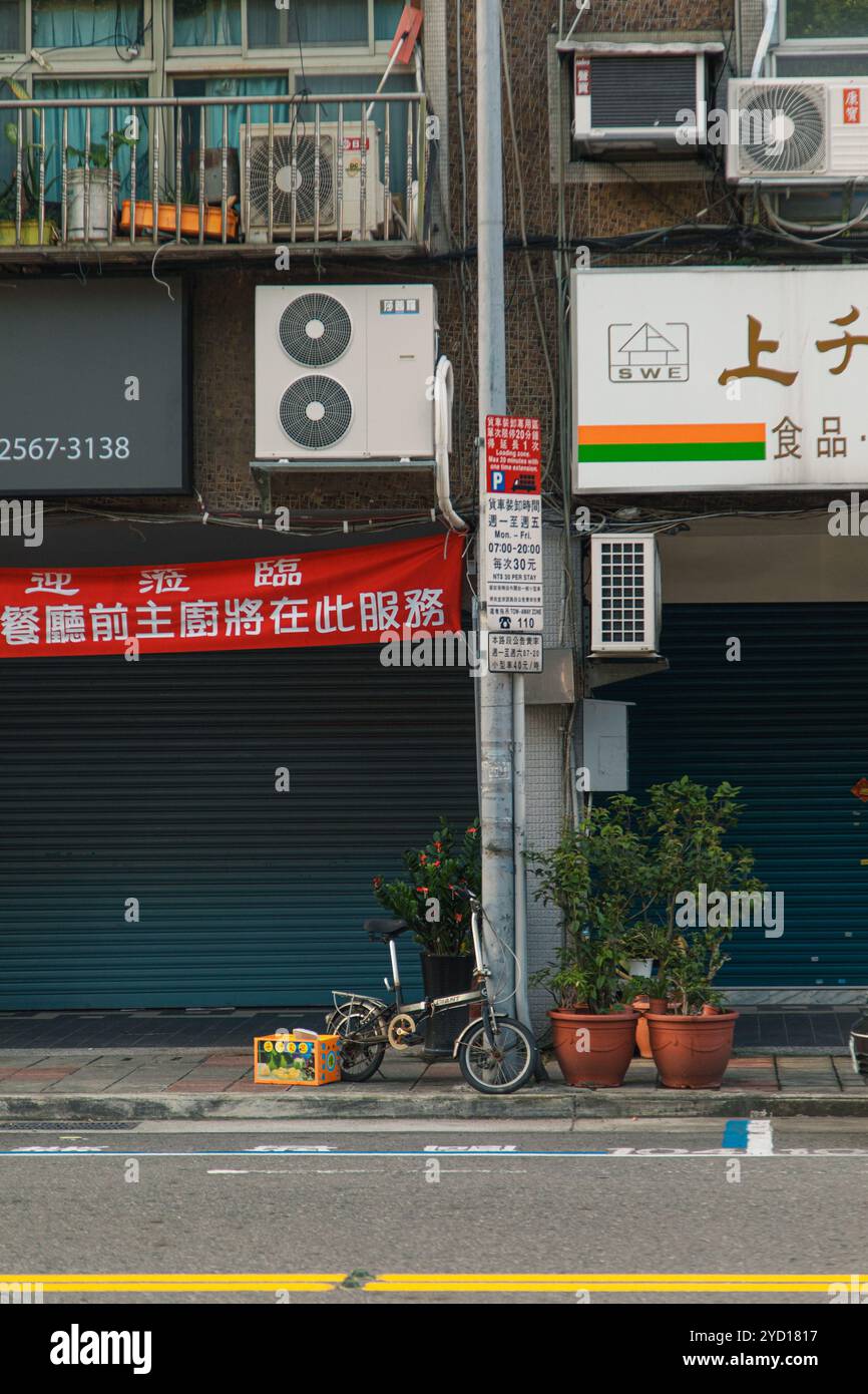 A tranquil street in Taipei shows closed storefronts with prominent ...