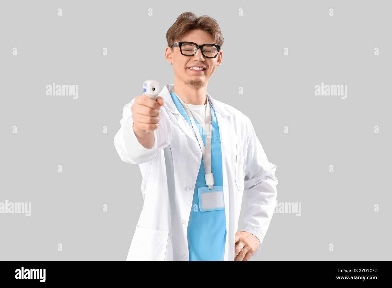 Male medical intern with infrared thermometer on light background Stock ...