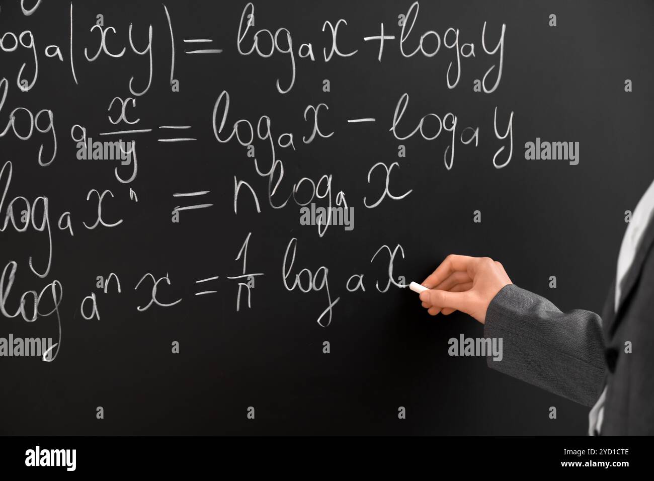 Female math teacher writing on blackboard in classroom Stock Photo - Alamy