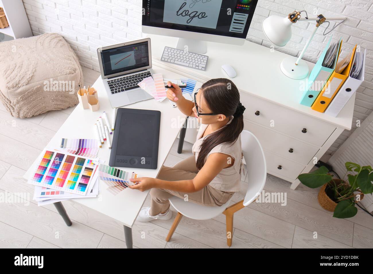 Female Asian graphic designer with color palettes working at table in ...