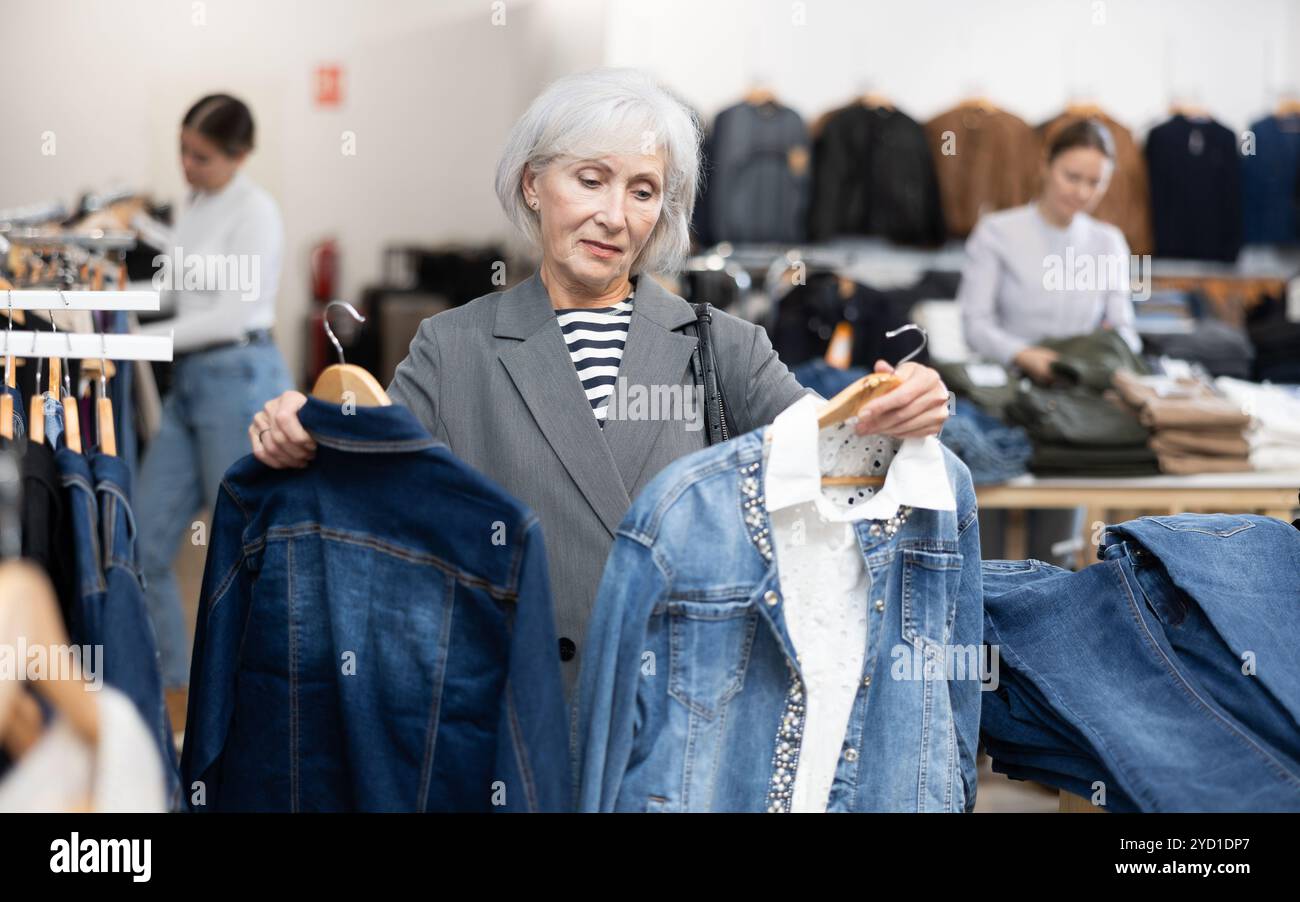 Old woman customer choosing jean jacket in clothing store Stock Photo ...