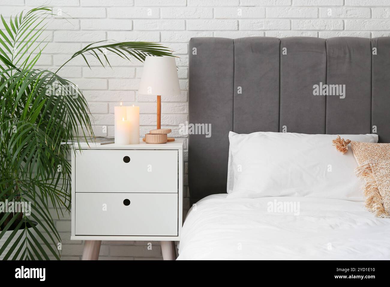 Burning candle on bedside table in bedroom Stock Photo - Alamy