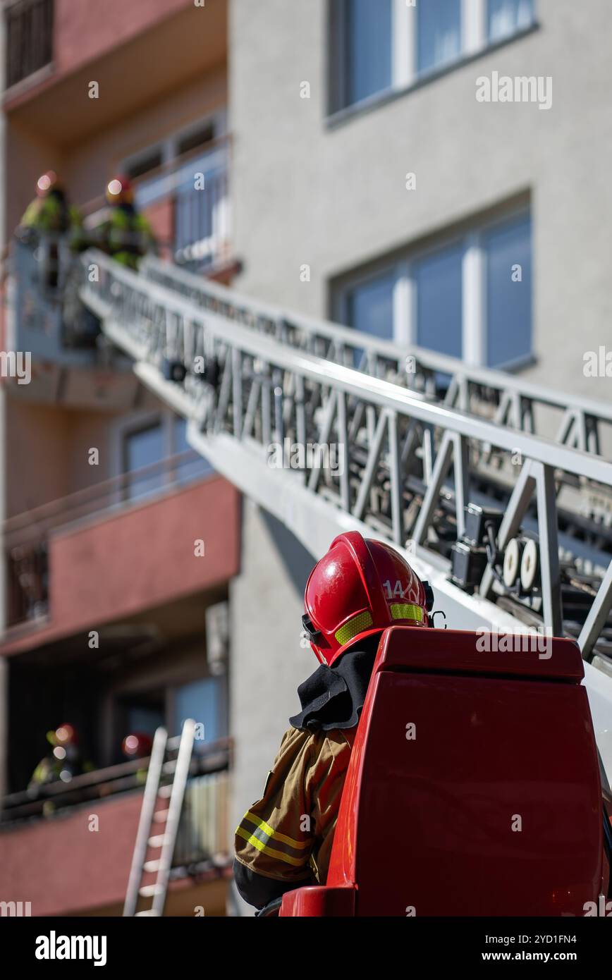 operator of fire truck with extended elevated ladder reaches up to ...
