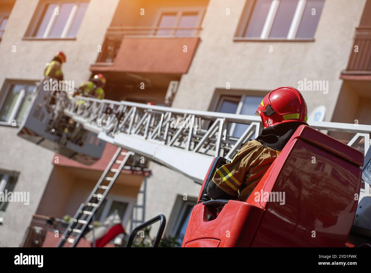operator of fire truck with extended elevated ladder reaches up to ...