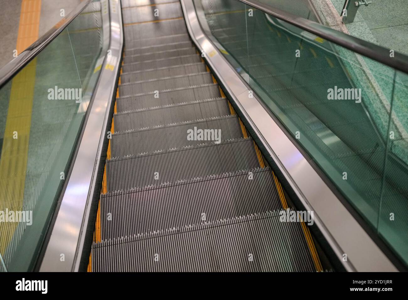 Long escalator with yellow stripes. The escalator is empty. The stairs ...