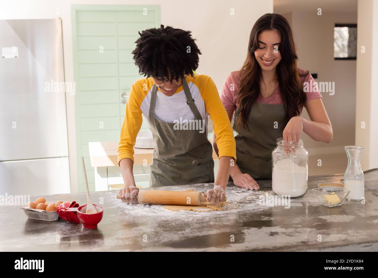 Christmas time, multiracial female friends baking, woman rolling dough ...