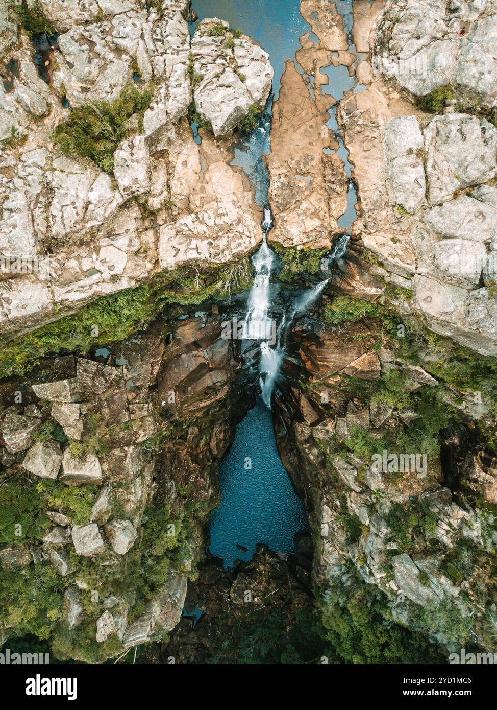 Overhead views waterfall flowing into rock pool at base of cliffs Stock ...