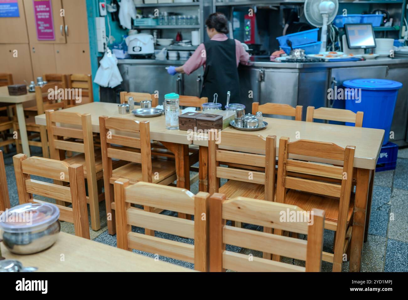 Woman is cooking in a restaurant. There are many chairs around a long ...