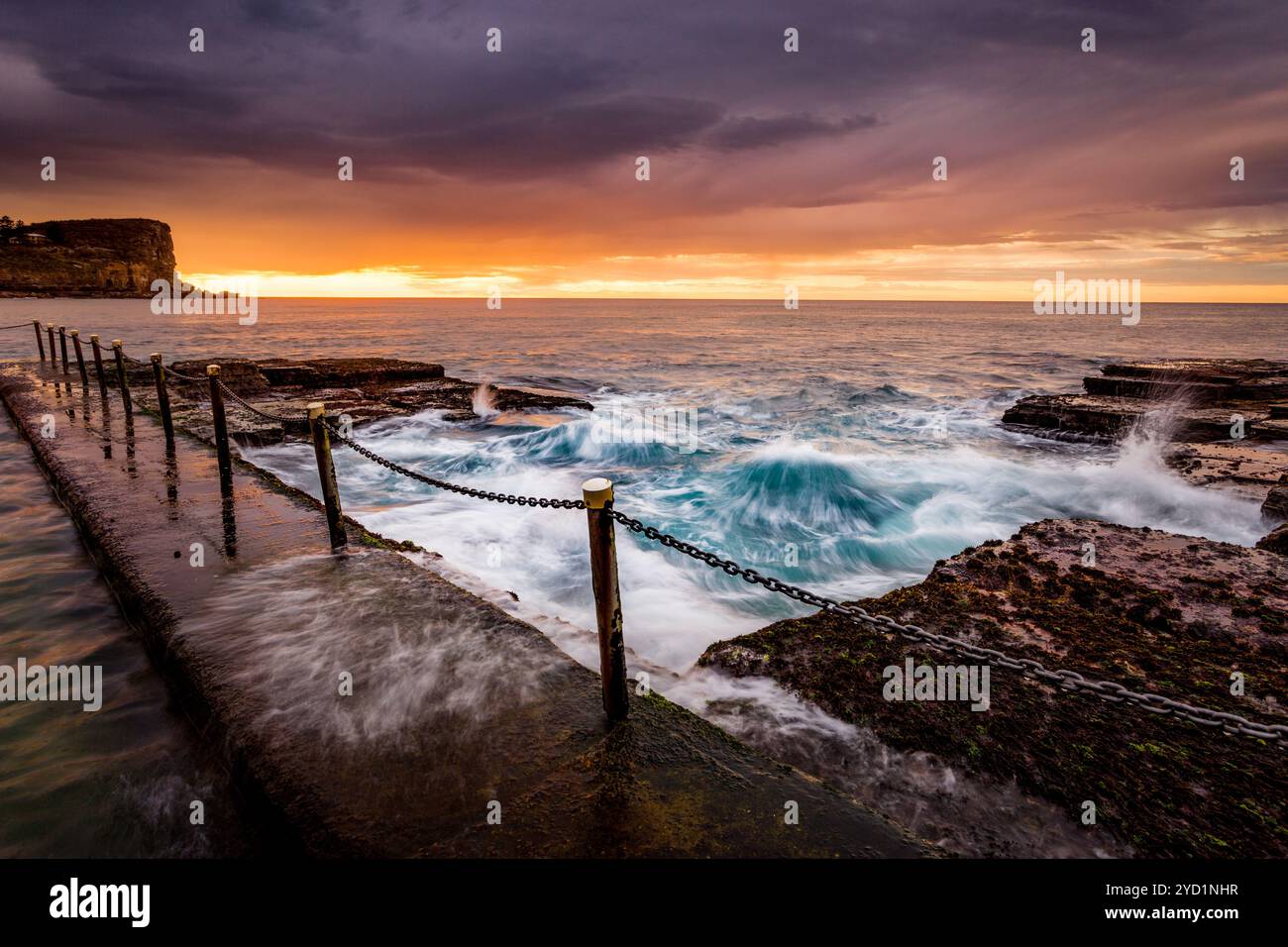 Coastal sunrise by the ocean rock pool with tidal flows over rocks and ...