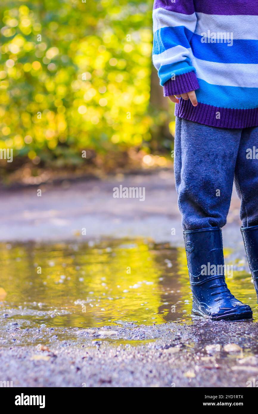 A little boy is jumping in a puddle. A boy in rubber boots. Happy ...