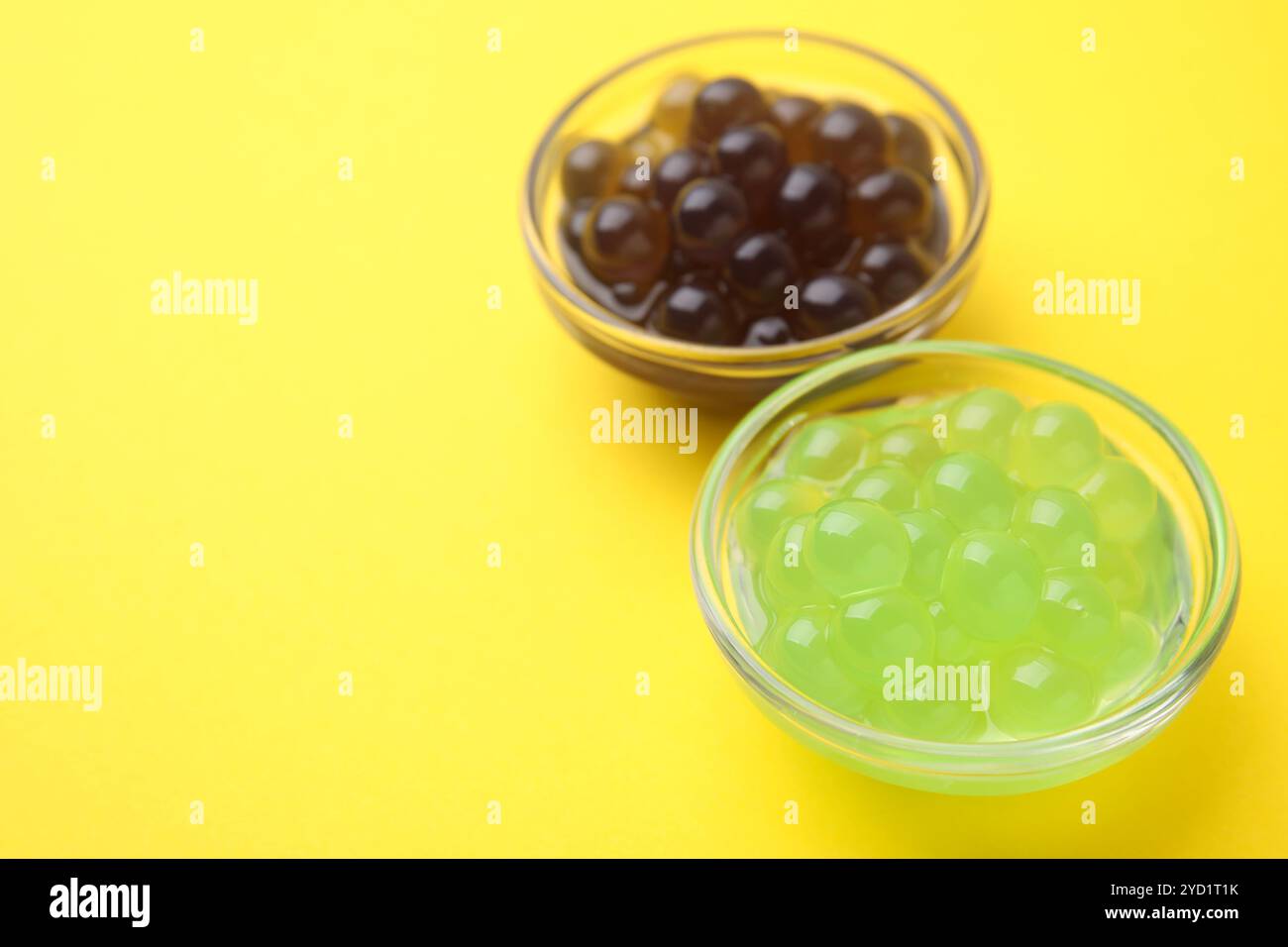 Color tapioca pearls in bowls on yellow background, closeup. Space for ...
