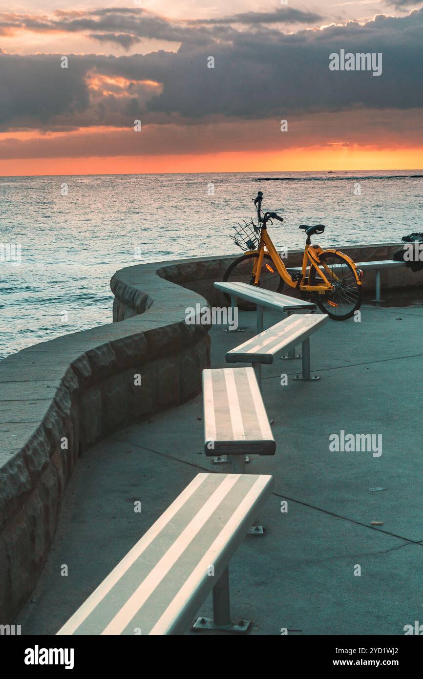 Bicycle and empty bench seats overlooking ocean at sunrise Stock Photo ...