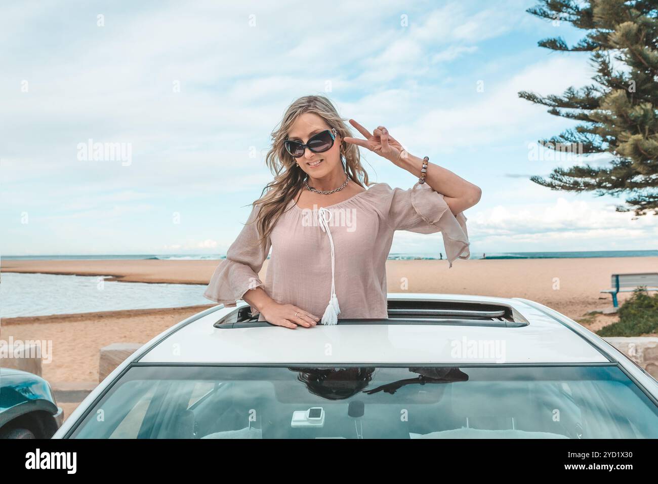 Fun loving woman enjoy travelling places in her car, she is standing in ...