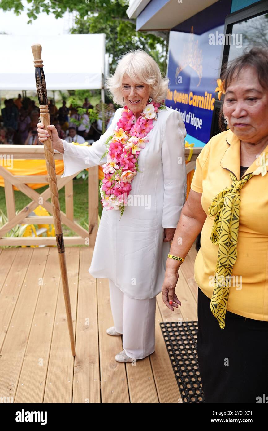 Queen Camilla holds a staff presented to her during a visit to the ...