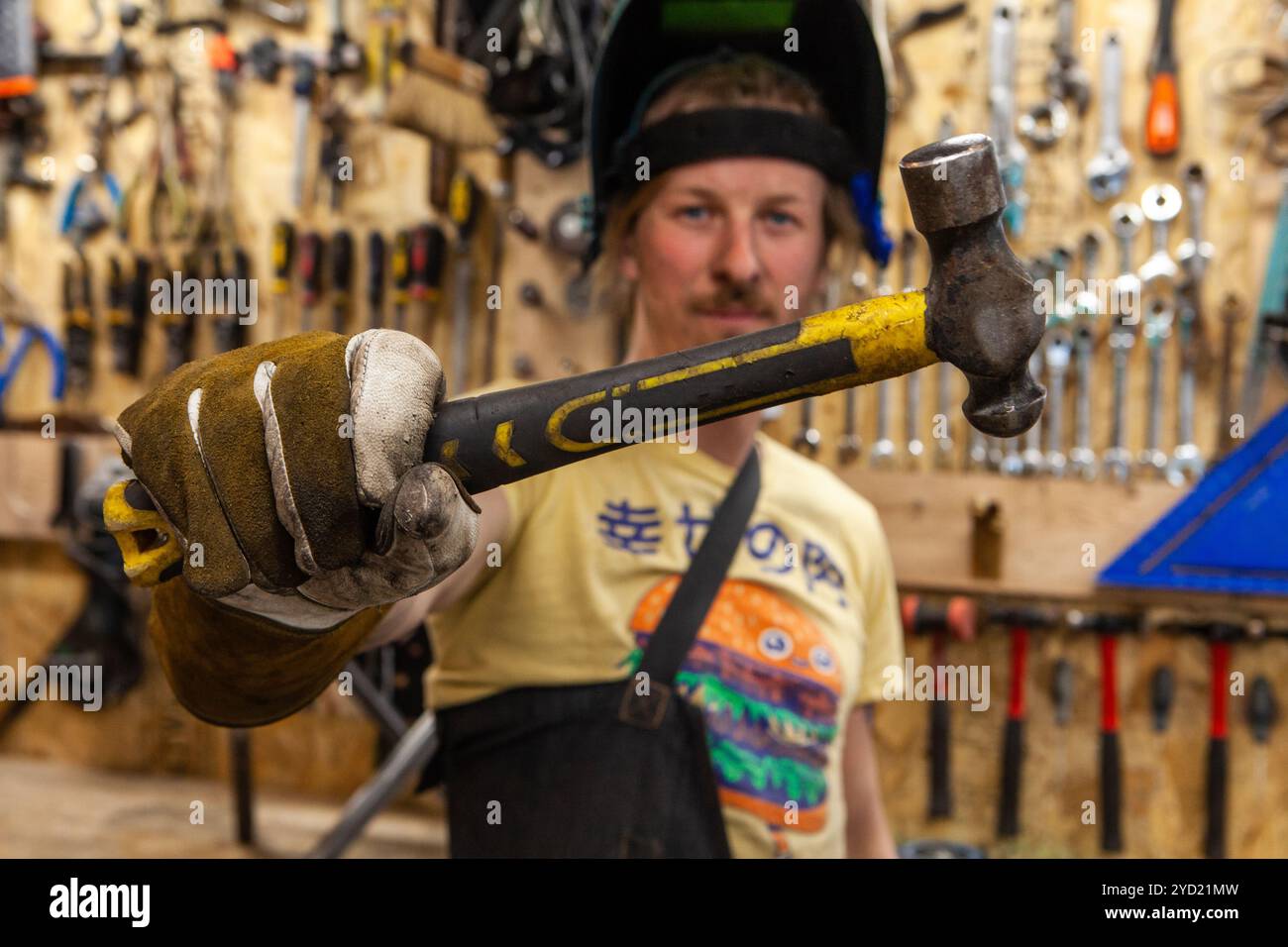 A front portrait view of a Caucasian blacksmith holding his hammer ...