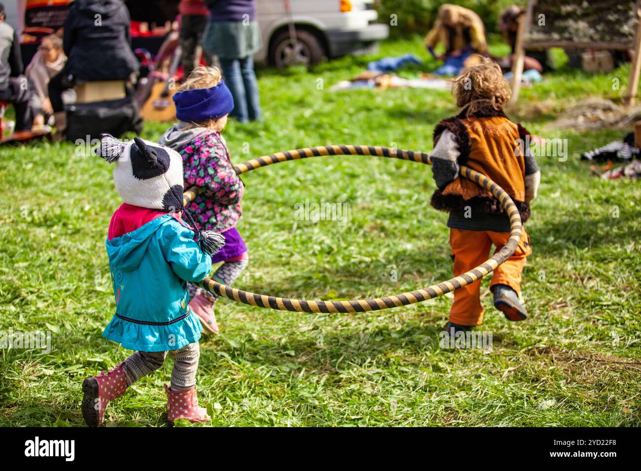 Three children are seen carrying a hula hoop through a campsite at a ...