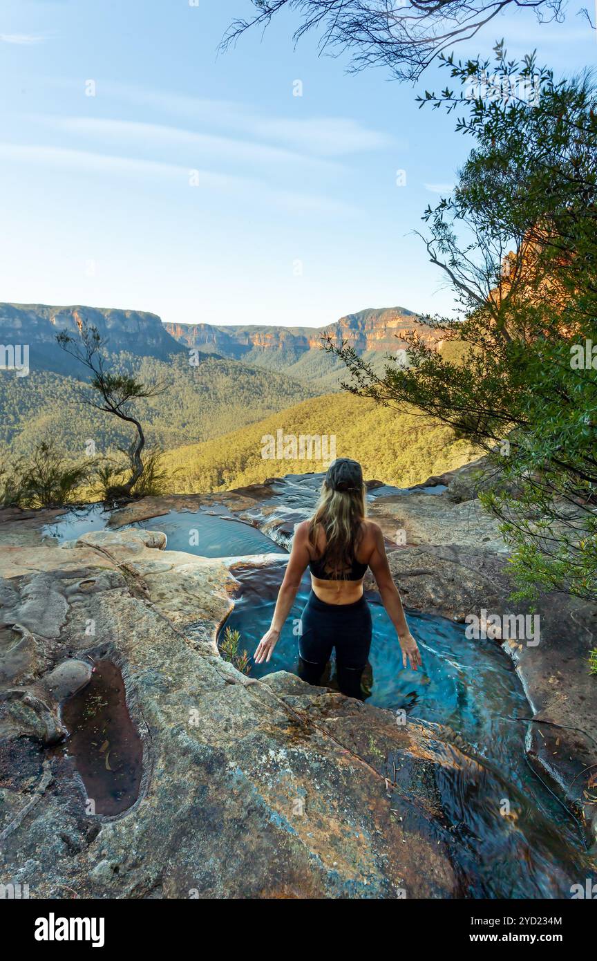 Female standing in plunge pools eroded into the rock ledge at the end ...