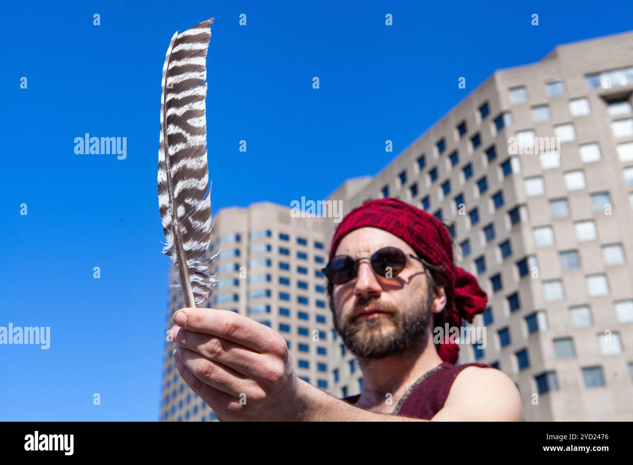 Boho man holds eagle feather in city Stock Photo - Alamy