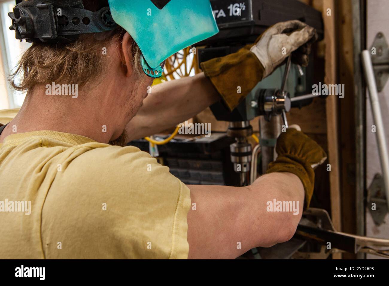 Metalworker operates drill press in shed Stock Photo - Alamy