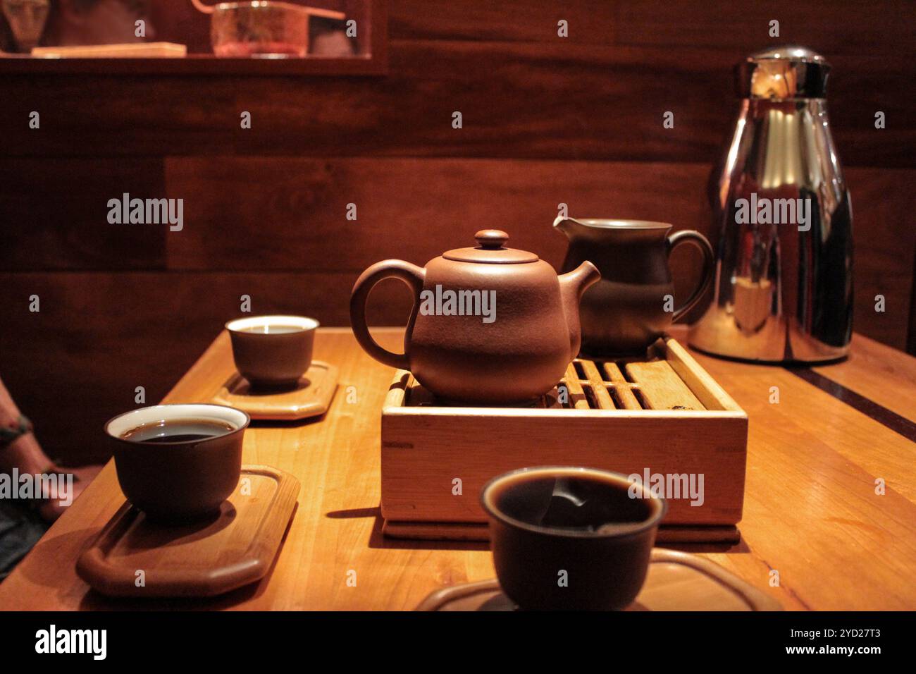 3 people tasting and drinking very dark pu-erh tea into small tasting ...