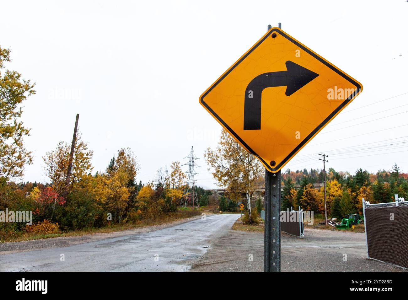 Turn right yellow road sign that is bent, dented, cracked and rusty ...