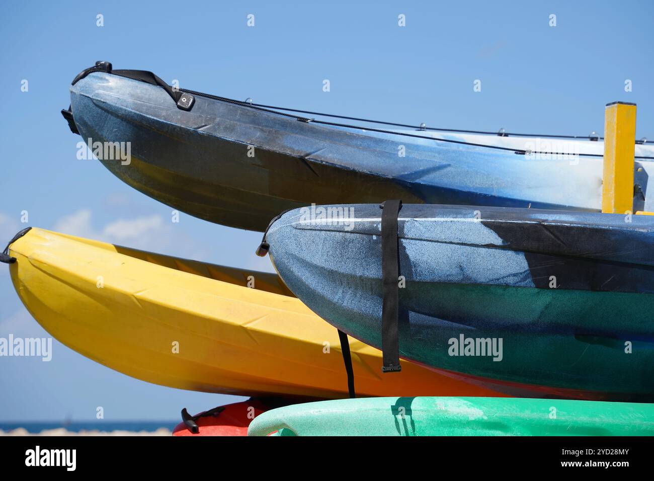 Colorful plastic boats stack on the beach. Multi-colored canoes and ...