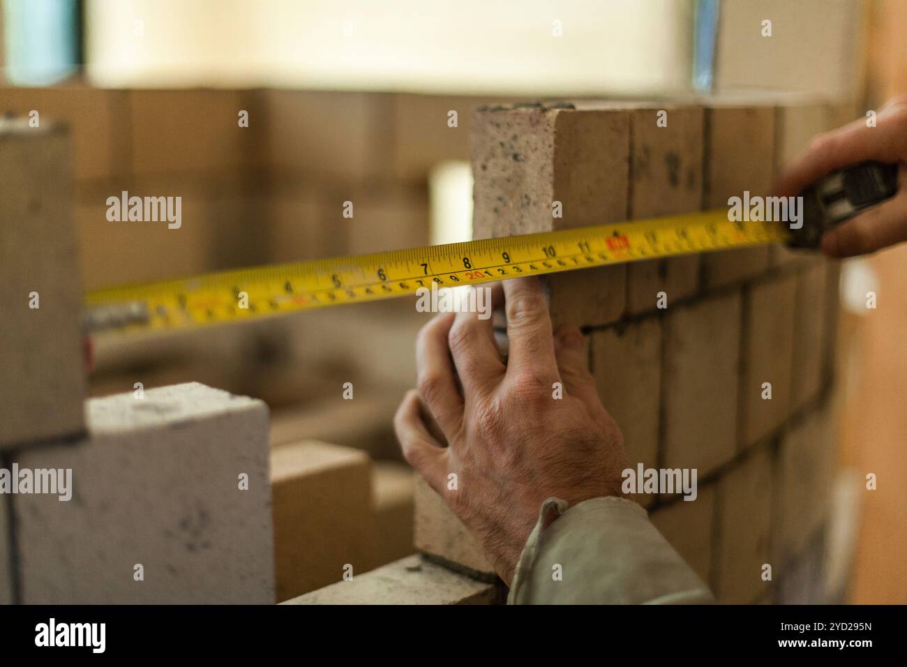 Man making measurements while working on his brick wall Stock Photo - Alamy