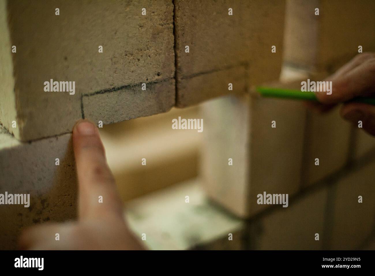 Man is measuring bricks while building a wall Stock Photo - Alamy