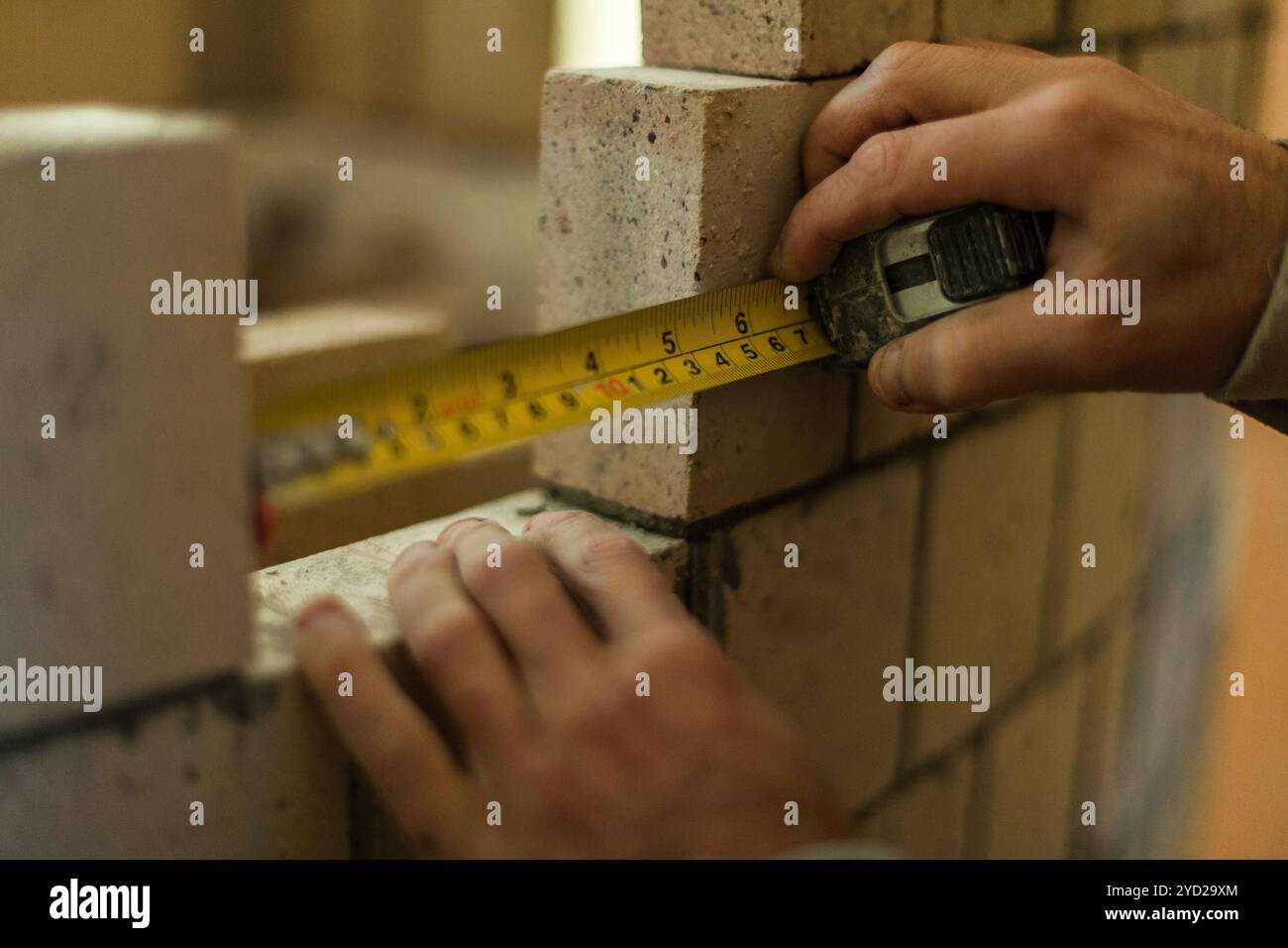 Brickmason holding a measuring tape to calculate the distance between ...