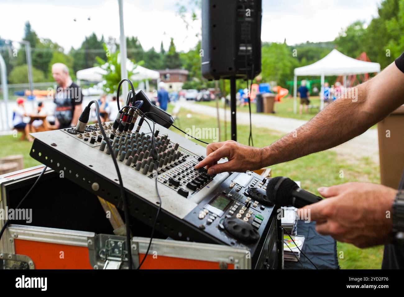 DJ is adjusting the levels on his mixing board during a community event ...