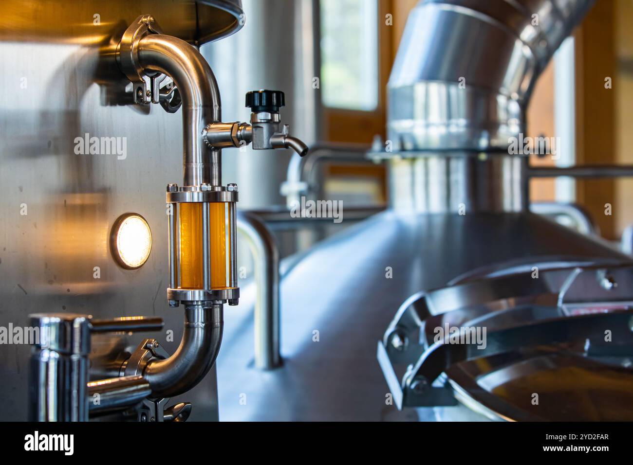 sight glass full of golden beer on stainless steel pipe with hose bib ...