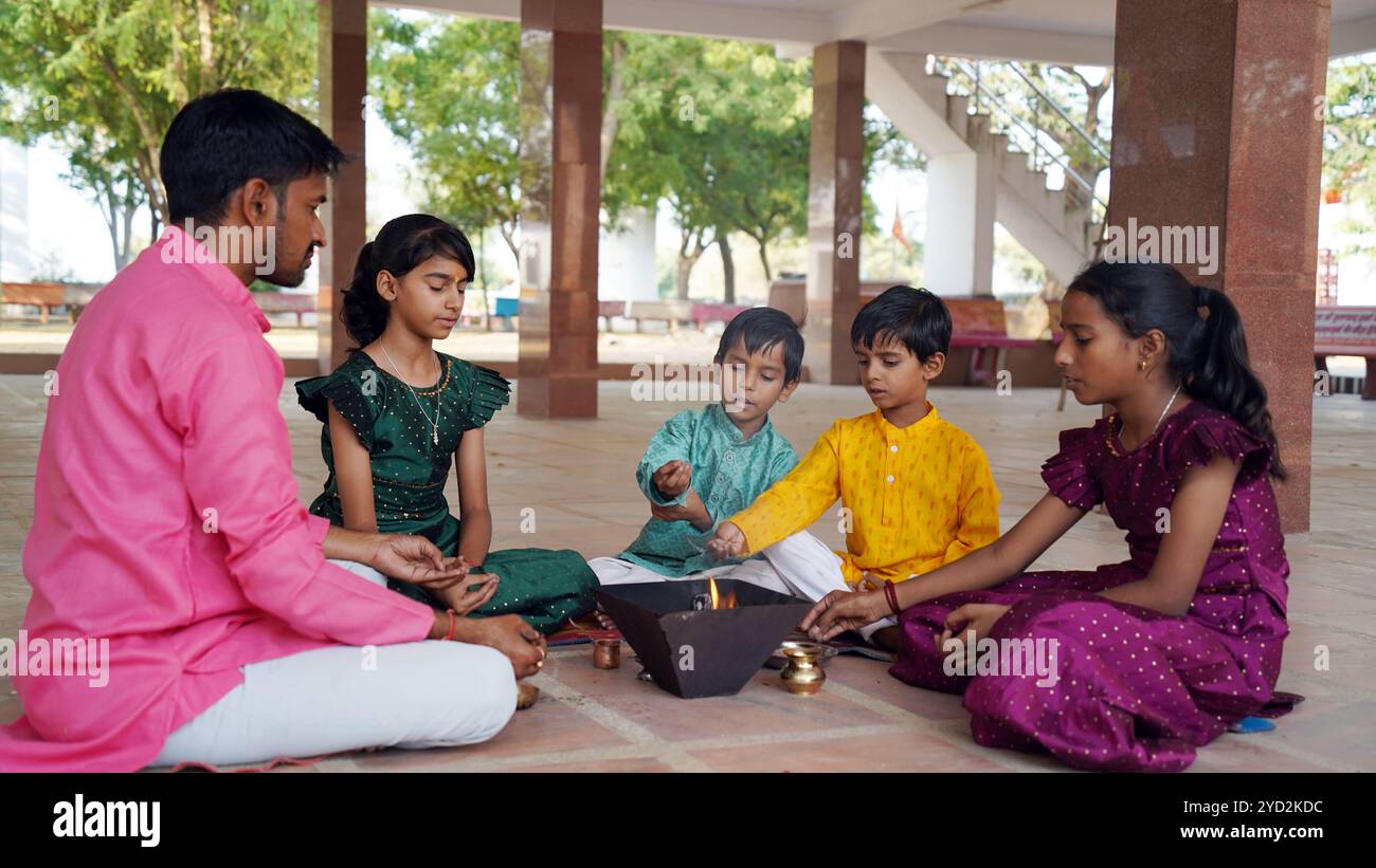 A Hindu family gathers around a sacred fire for Yagya during a festival ...