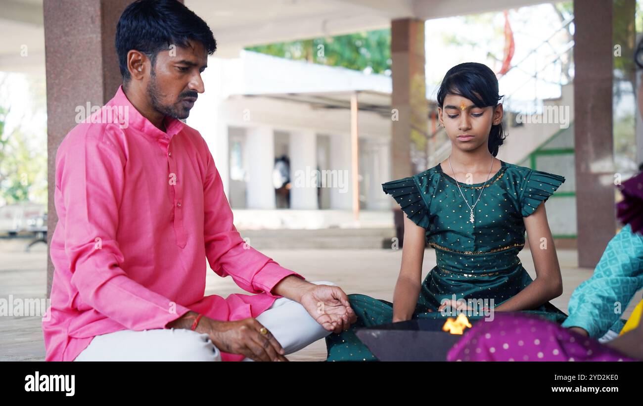 A traditional Indian family engaged in a sacred Yagya ritual to ...