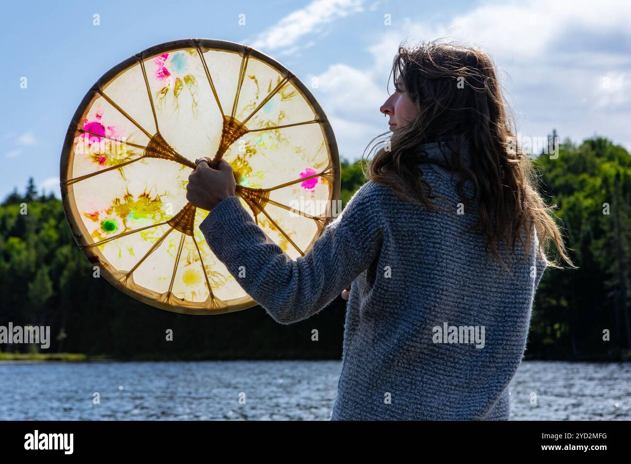 Side Rear view of young shamanic woman holding sacred native frame drum ...