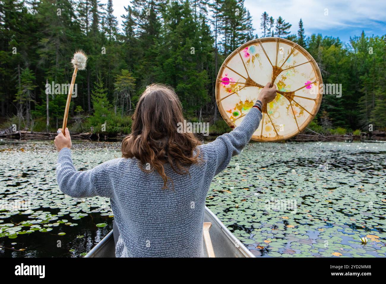 Woman holding sacred drum and stick in canoe Stock Photo - Alamy