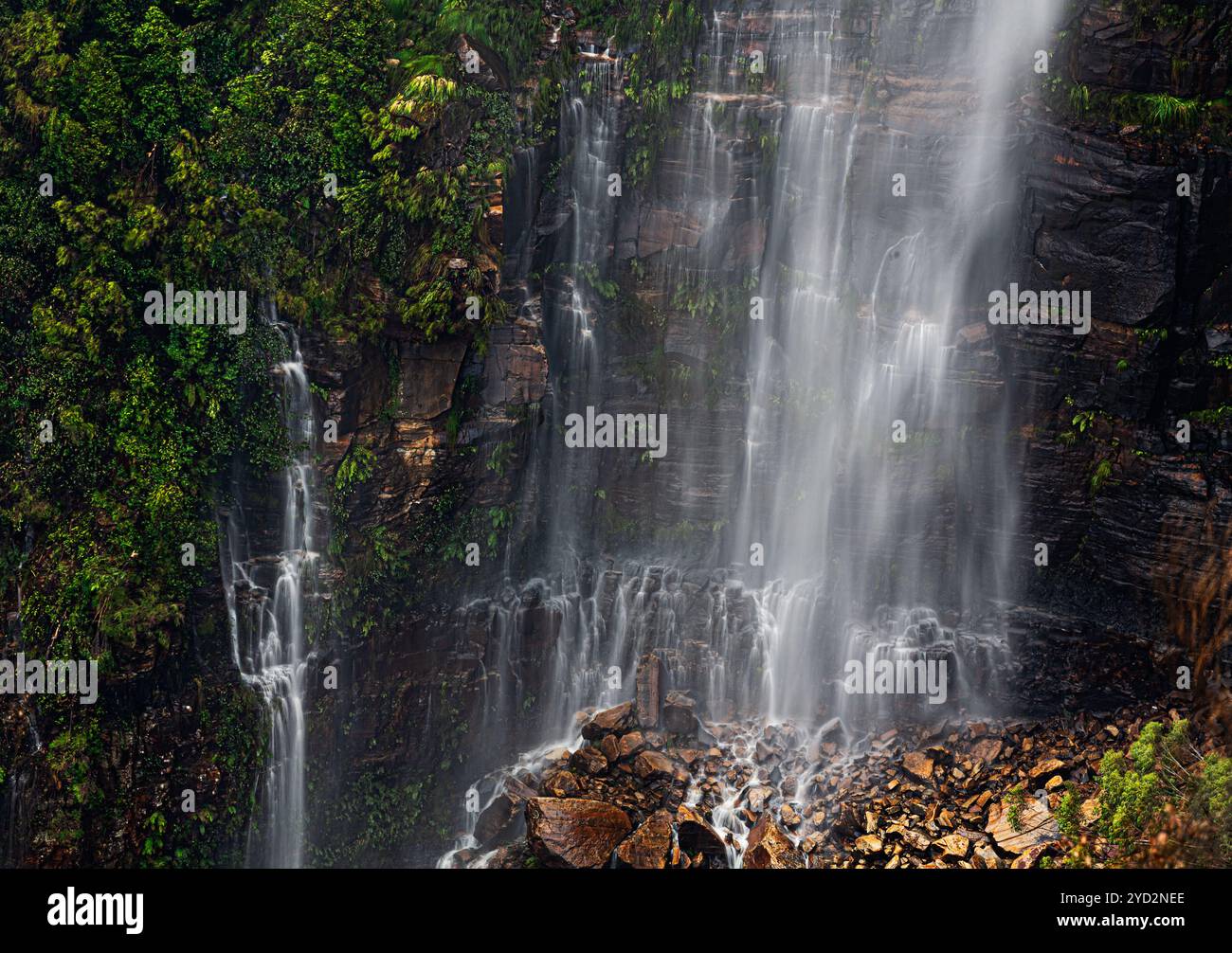 Waterfall cascading onto a rocky rubble at its cliff base Stock Photo ...