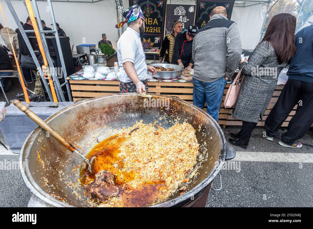 Cooking appetizing traditional oriental pilaf in a large cauldron Stock ...