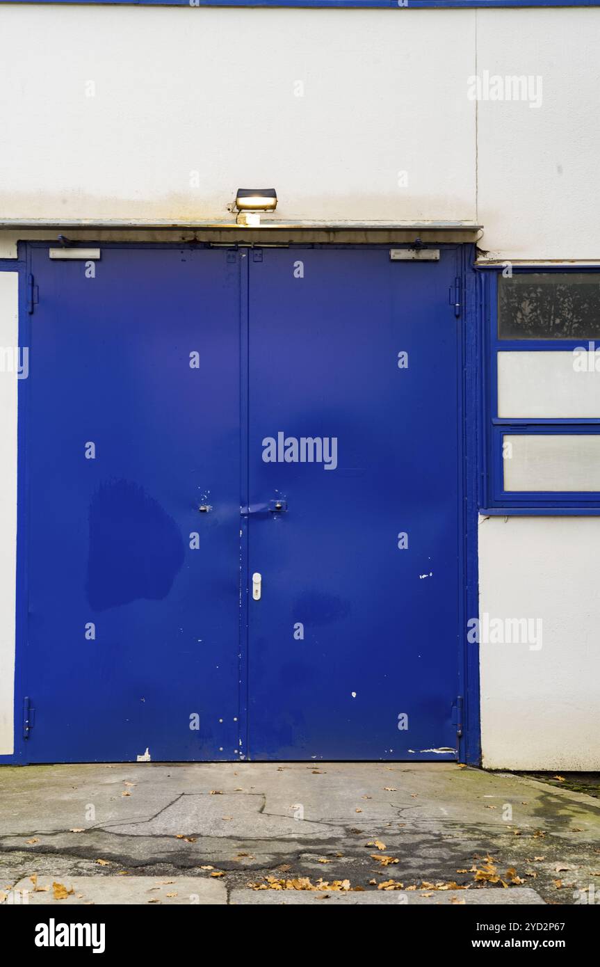 Blue industrial swing gate on a white building with security lighting ...