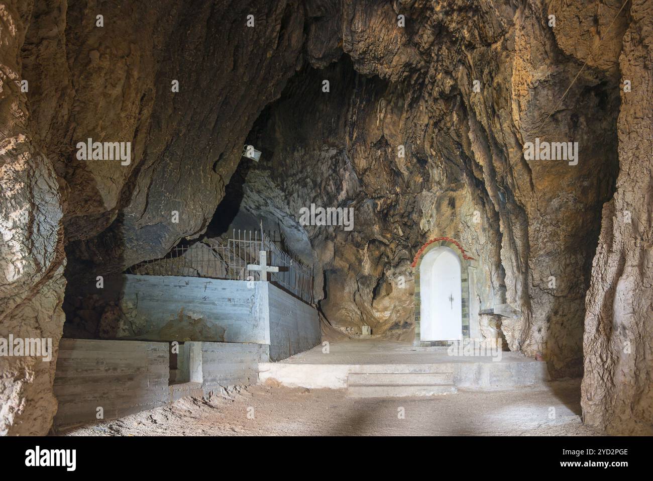 Interior view of a rocky cave with a tomb and a cross, a white niche ...