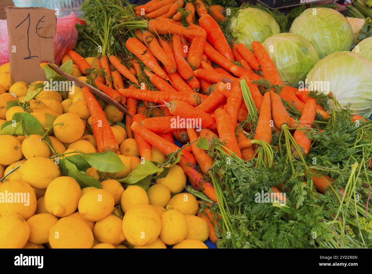 Market stall with fresh vegetables such as carrots, lemons and cabbage ...