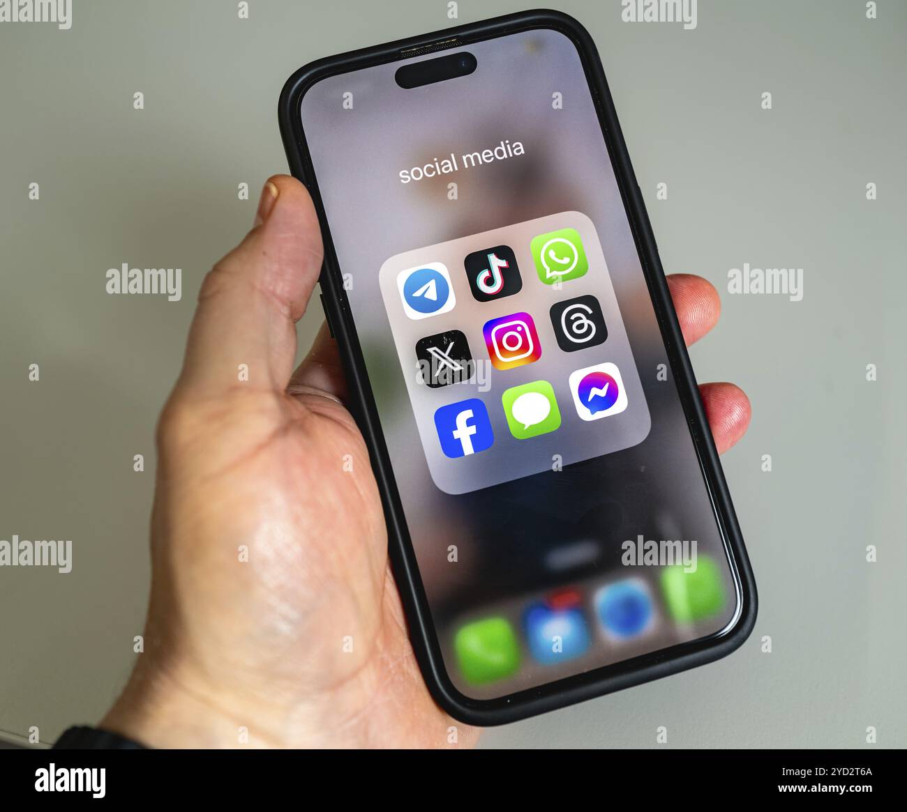 A smartphone is held in the hand and shows app icons, display on a ...