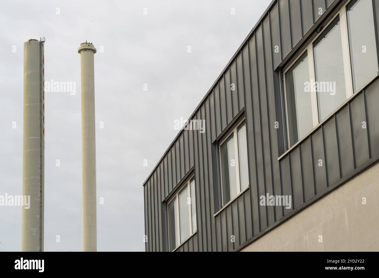 A modern office building with a dark metal facade stands near two ...
