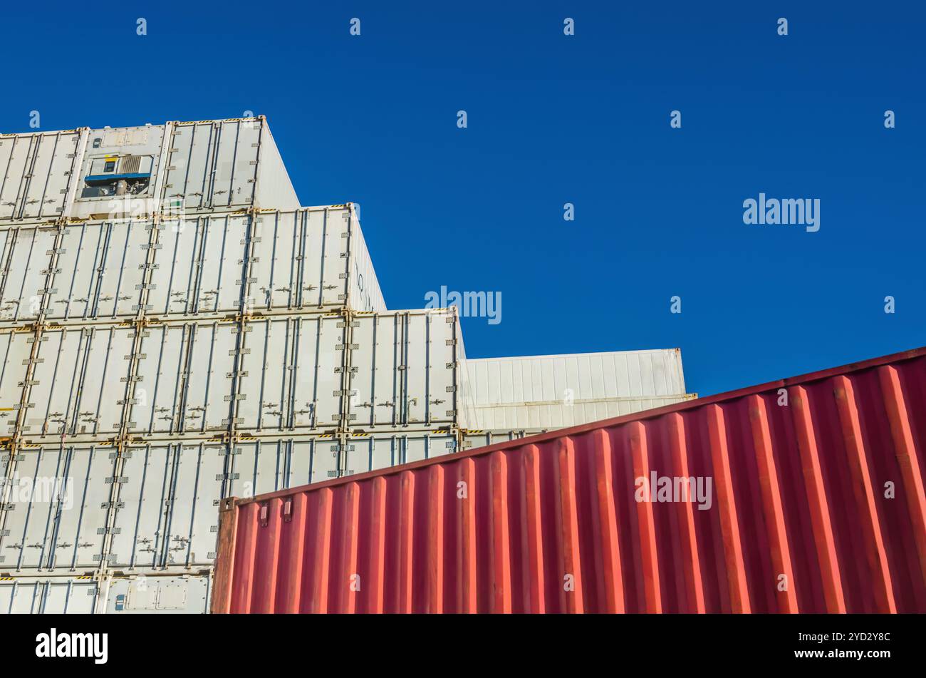 Stack of white refrigerated cargo containers against a clear blue sky ...