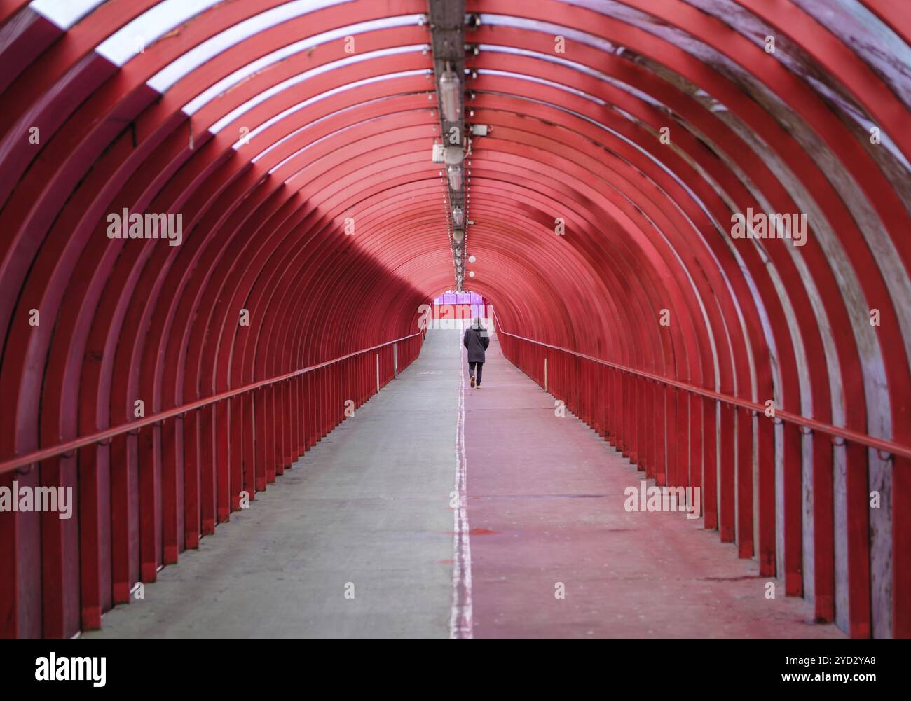 A Man Walking Alone Through A Covered Walkway At An Airport Or Train ...