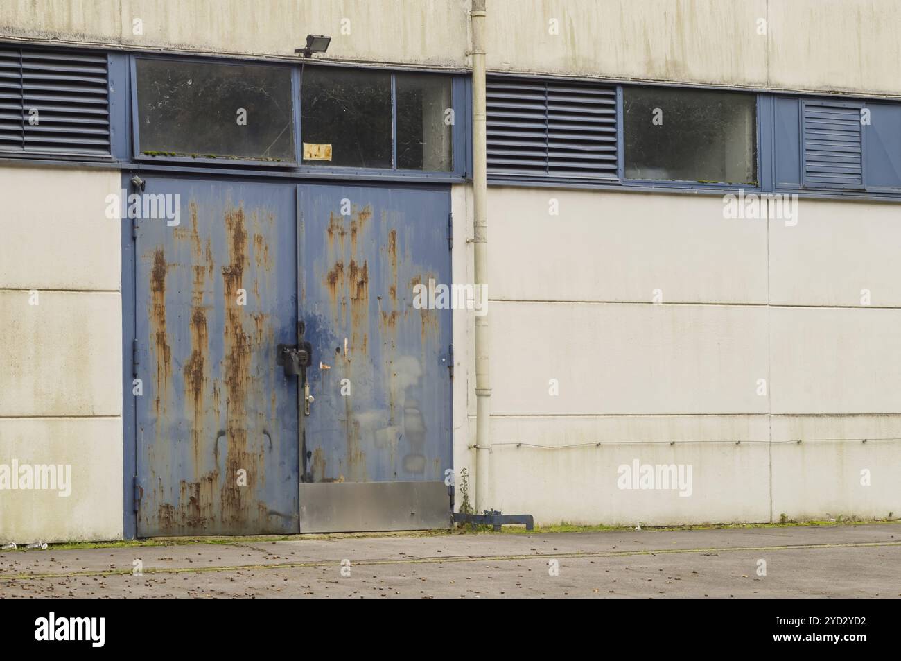 Rusty old blue industrial gate with padlock and window showing decay ...