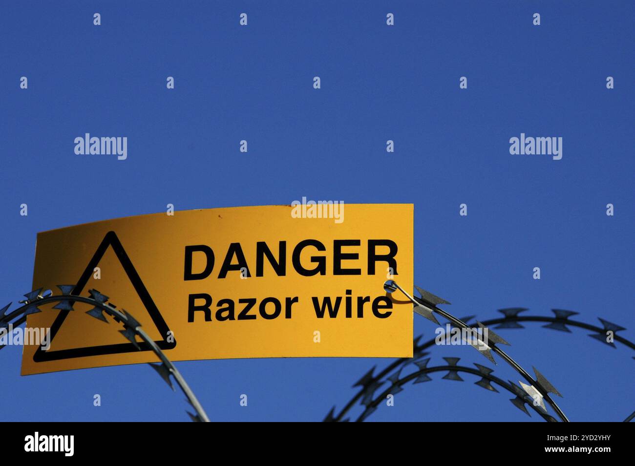 A warning sign on some razor wire Stock Photo - Alamy