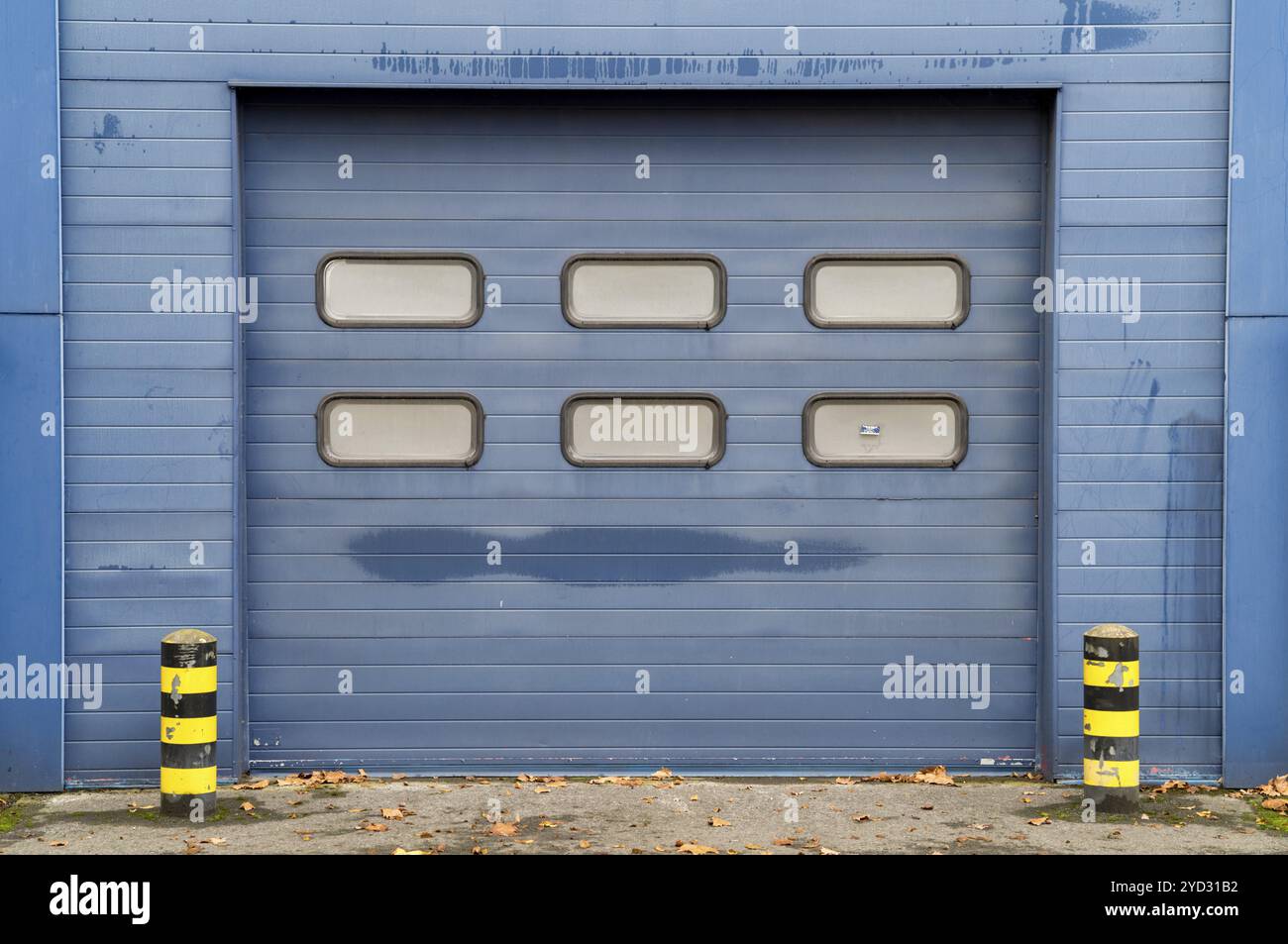 The blue industrial garage door with six windows shows its age with ...