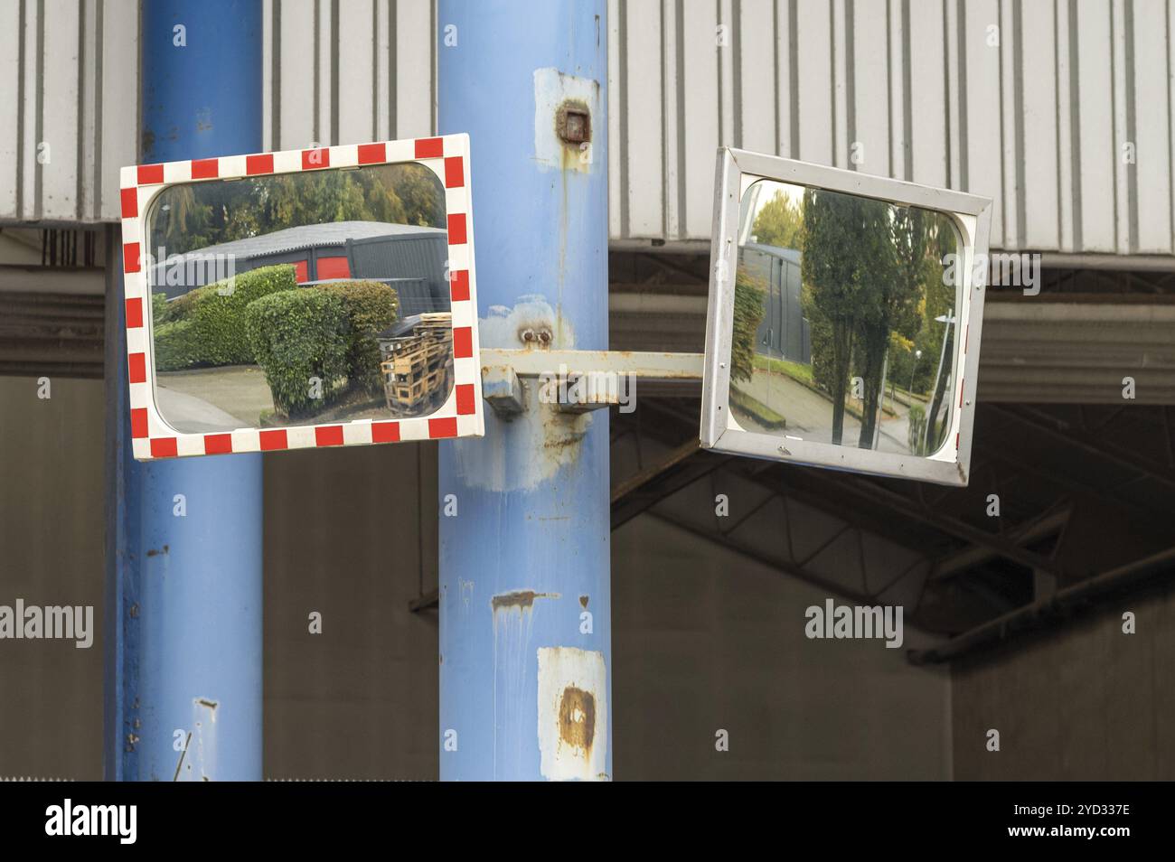 Two convex safety mirrors are mounted on a blue mast and reflect the ...